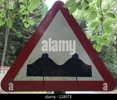 Defaced Uneven Road sign Stock Photo - Alamy
