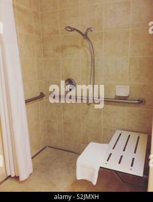 Wheelchair accessible hotel bathroom shower with tile floor and walls ...