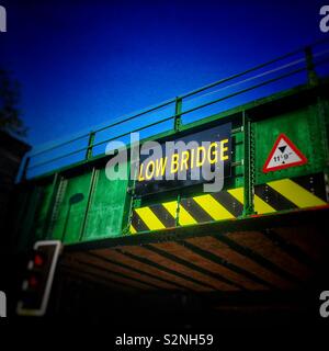 Low railway bridge with black and yellow markings Stock Photo - Alamy
