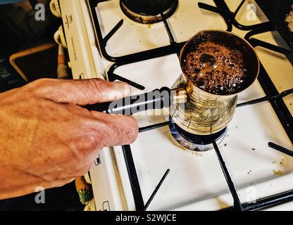 Man making Lebanese coffee in traditional brass coffee pot. Called a ...