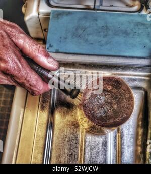 Man making Lebanese coffee in traditional brass coffee pot. Called a ...