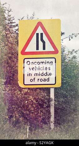 Road signs for road narrowing and oncoming vehicles in middle of road ...