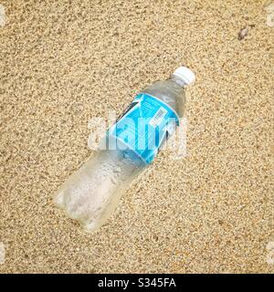 Partially buried plastic water bottle on the beach at Batu Rakit ...