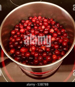 Fresh cranberries cooking on stove top with sugar and orange zest peel ...
