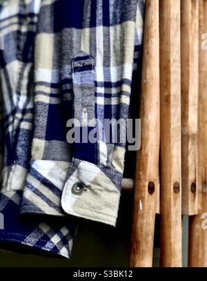 Blue plaid flannel shirt on wooden clothes rack by window Stock Photo ...
