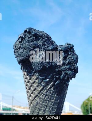 Black charcoal ice cream in a female hand on a blue background Stock ...