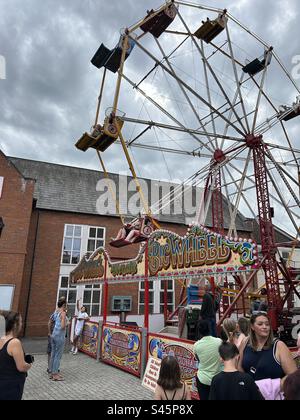 Fairground in the village square, England, July 2023. Carnival rides ...