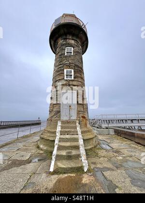 Weathered stone lighthouse on the east pier at Whitby, North Yorkshire ...