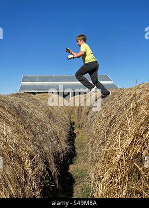Rows of large round hay bales stacked in a pile with wispy clouds and ...