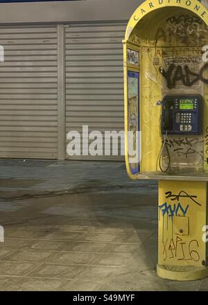 A vandalized and neglected public telephone booth covered with graffiti ...
