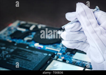 Technician repairing broken laptop notebook computer with screwdriver ...