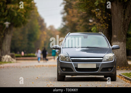 Gray shiny car parked in quiet area on asphalt road on blurred bokeh ...