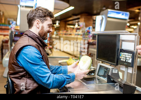 Man working at cash counter of a supermarket. Teenage cashier working ...