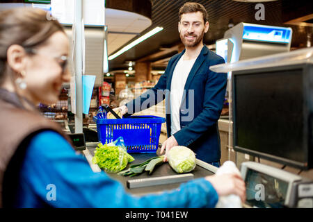 Handsome businessman putting products on the cash register buying food ...