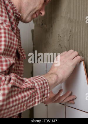 Contractor installing tiles on a wall Stock Photo - Alamy