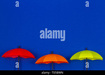 Small colorful umbrellas on blue color background Stock Photo - Alamy
