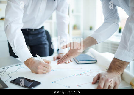 Group of young contemporary engineers discussing sketch in blueprint ...