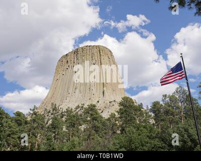Wide shot of the Devils Tower, with a United States flag flying nearby ...