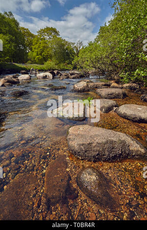 An upland river flowing over and around boulders as it flows downhill ...