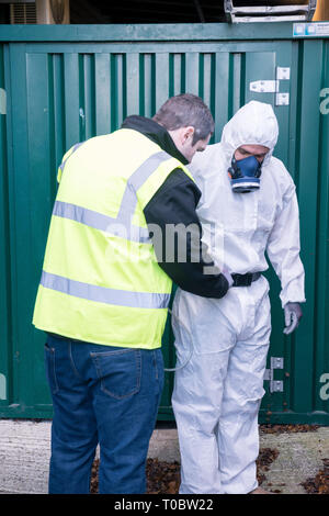 An environmental safety equipped worker in a paper body suit with ...