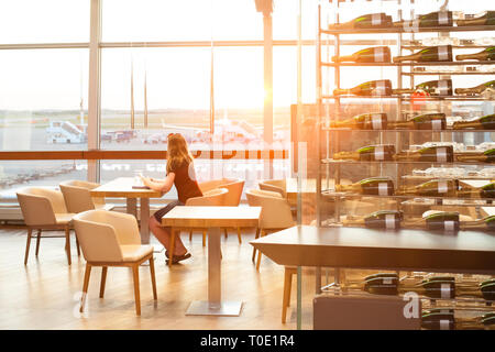 Woman waiting for flight at airport terminal Stock Photo - Alamy