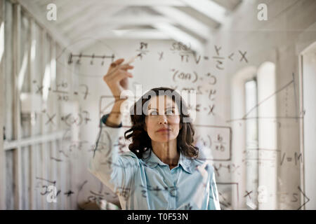 A young woman looking at a mathematical equation written out with Stock ...