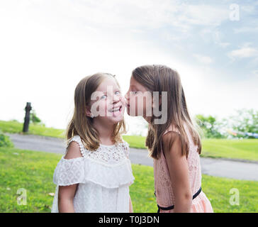 Two cute blond sisters kissing outdoors Stock Photo - Alamy