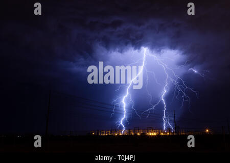 Bright lightning bolts striking electric power pylon tower cables and ...