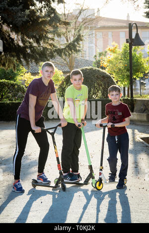 Boy riding scooters, outdoor in the park, summertime. Kids are happy ...