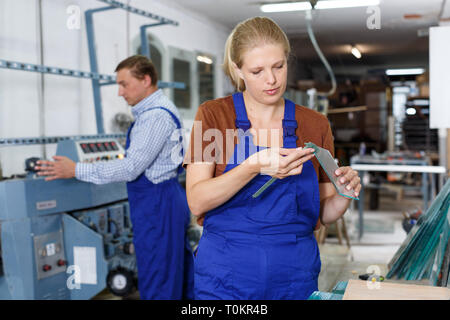 Qualified female glazier using caliper for measuring glass size in ...