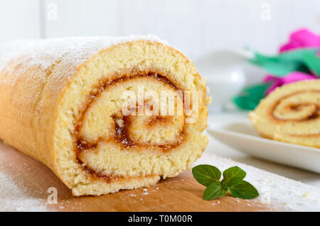 Delicious biscuit roll with apricot jam on a white wooden table ...