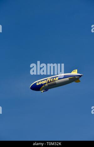 Famous Goodyear blimp dirigible soaring overhead in flight in bright ...