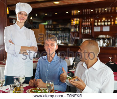 Confident female chef talking with satisfied male company lunching in ...