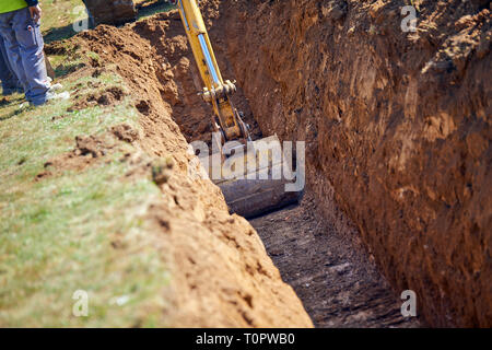 Working excavator tractor digging a trench for pipenlineat at ...