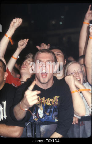 Front row heavy metal fans are shown with their arms in the air during ...