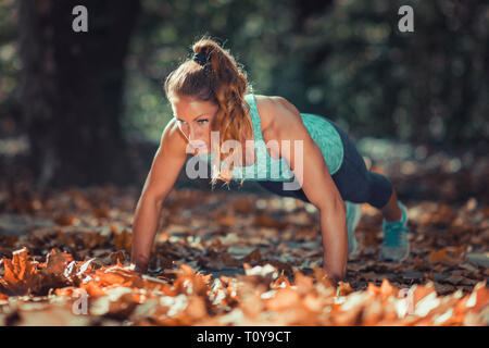 Adult woman in sportswear doing yoga on the lawn in a park on a sunny ...