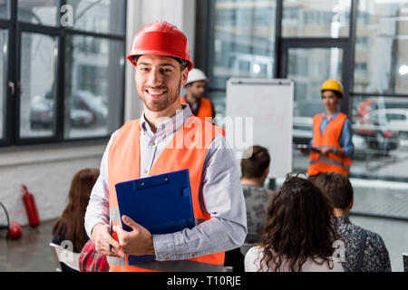 selective focus of cheerful fireman holding clipboard near coworker ...