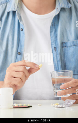 Man taking his pills on couch in the living room Stock Photo - Alamy
