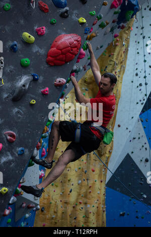 A rock climbing instructor climbs an indoor climbing wall Stock Photo ...