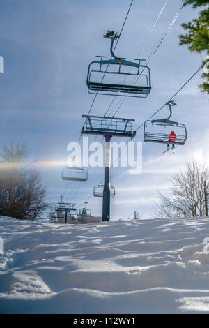 Chair-lift and sunlit sky with clouds at winter evening. Panoramic view ...