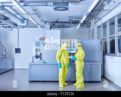 Chemists working in industrial laboratory, wearing protective clothing ...