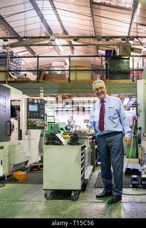 A friendly older gentleman / business owner standing in and on the ...
