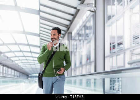 Businessman on a moving walkway, using smartphone Stock Photo - Alamy