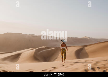 Namibia, Namib, back view of woman walking barefoot on desert dune ...