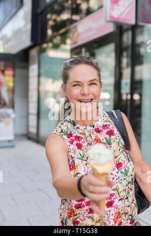 smiling woman with ice cream at city street Stock Photo - Alamy