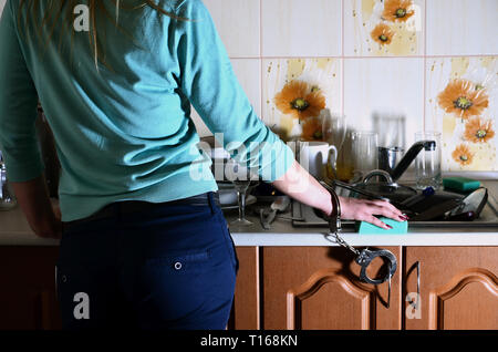 A girl with a sponge in her hand, handcuffed to the kitchen counter ...