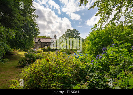 A small stone cottage in lush green countryside with hills under blue ...