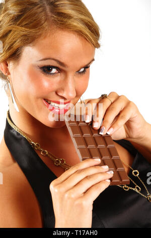 Young beautiful woman eating chocolate donut over yellow background ...
