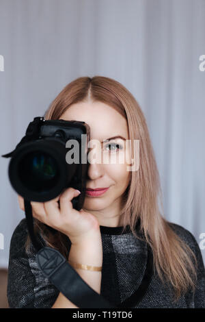 Portrait of photographer covering her face with camera. Woman taking ...