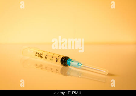 Injection syringe on a clean orange background Stock Photo - Alamy